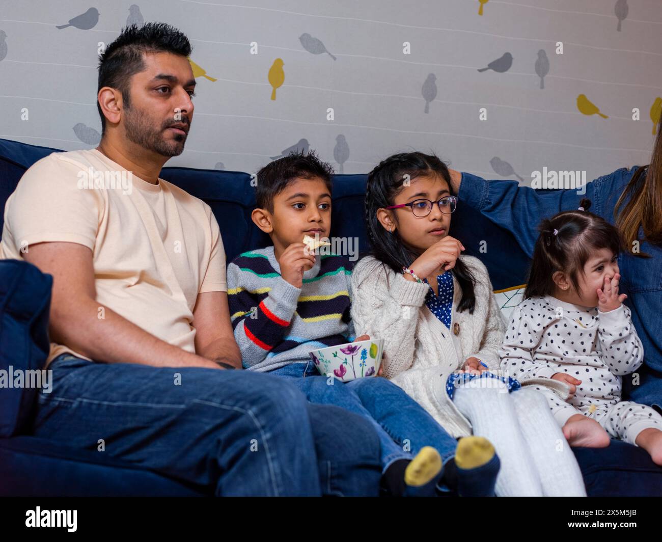 Parents with children sitting on sofa and watching TV Stock Photo - Alamy