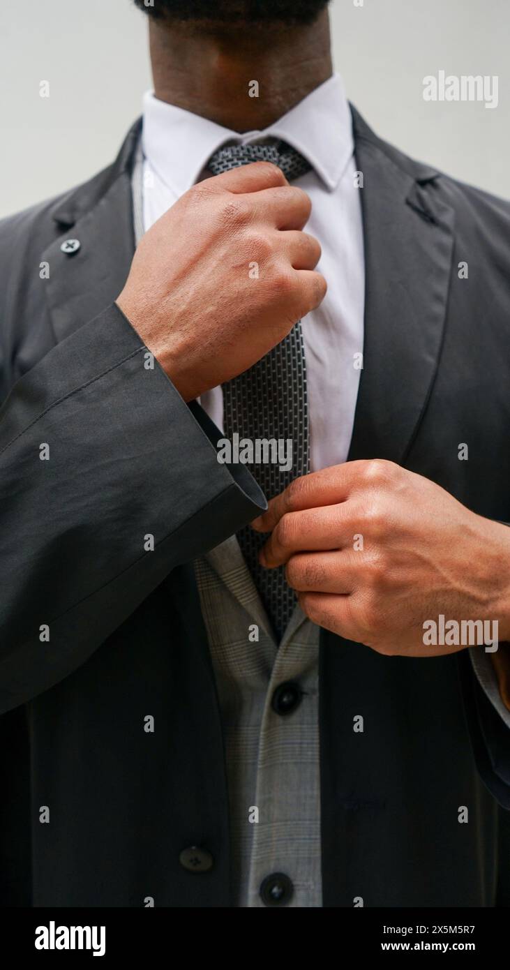 Midsection of business man adjusting necktie Stock Photo - Alamy