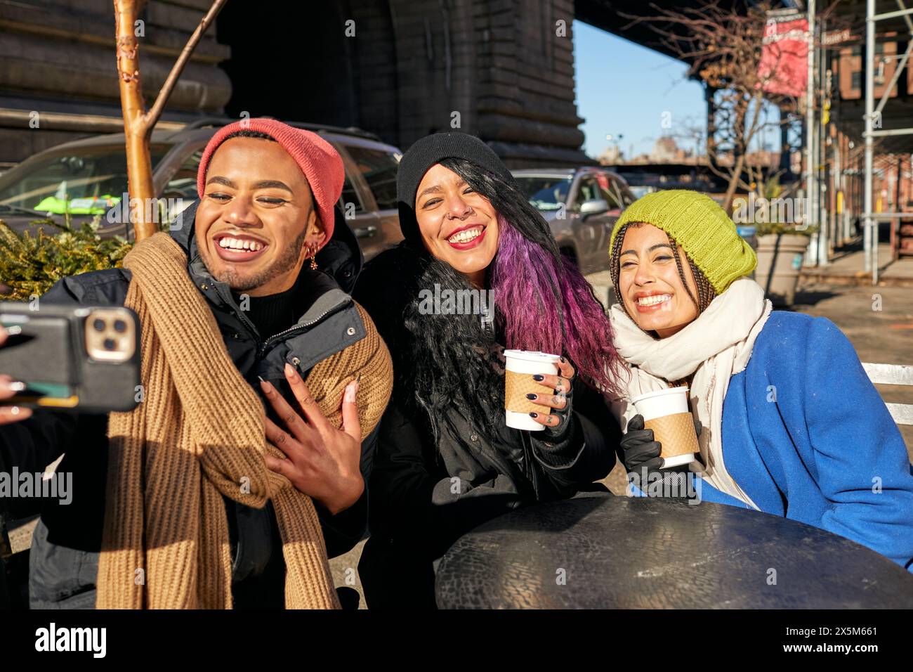 USA, New York City, Smiling friends taking selfie at sidewalk cafe ...