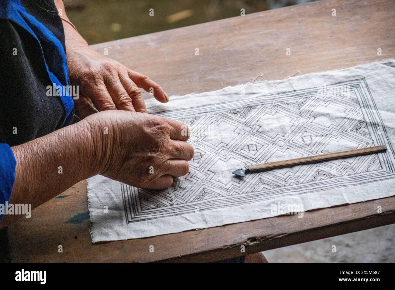 A Flower Hmong woman draws a pattern for her traditional embroidery, Mu ...