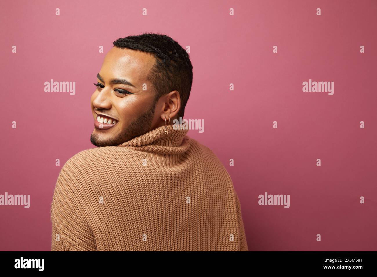 Studio portrait of smiling queer man against purple background Stock ...