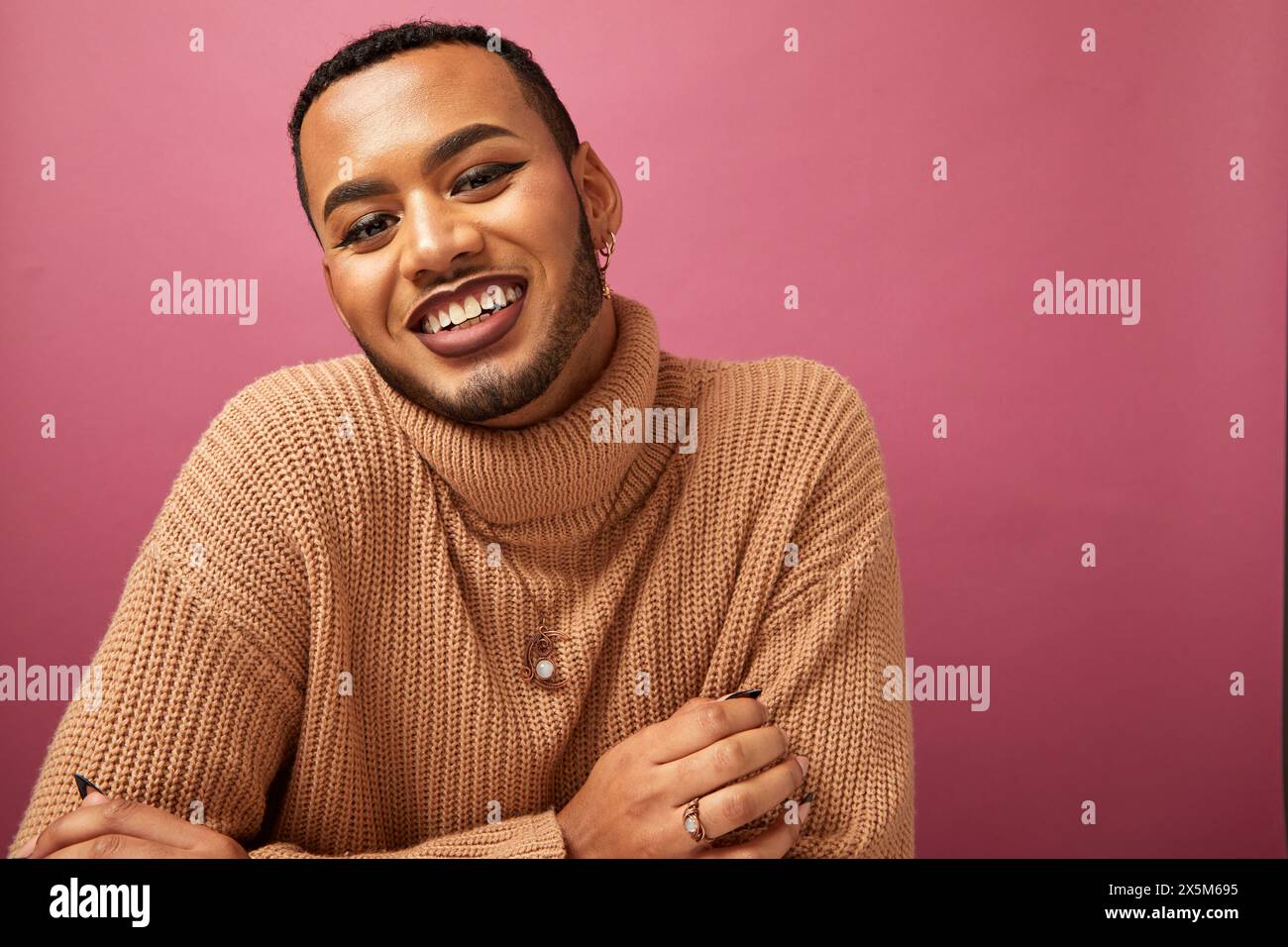 Studio portrait of smiling queer man against purple background Stock ...
