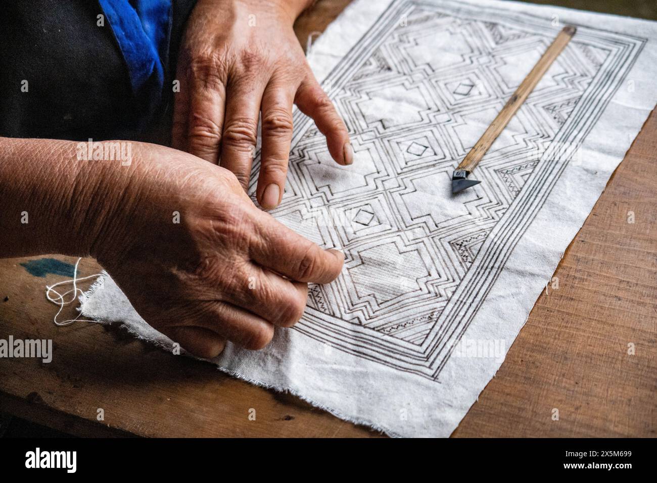 A Flower Hmong woman draws a pattern for her traditional embroidery, Mu ...