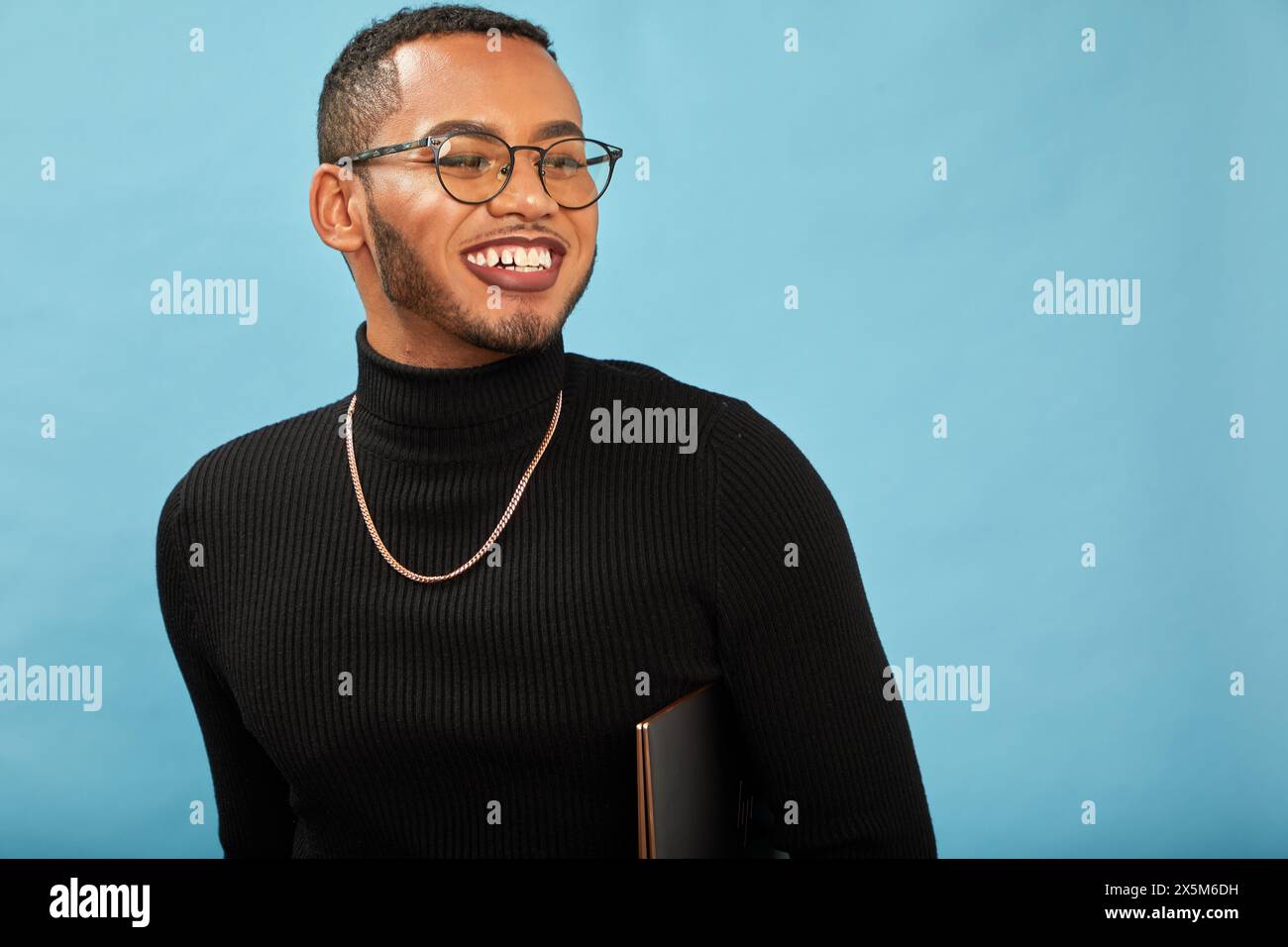 Studio portrait of smiling queer man with laptop Stock Photo - Alamy