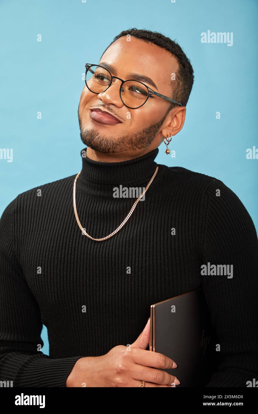 Studio portrait of smiling queer man with laptop Stock Photo - Alamy