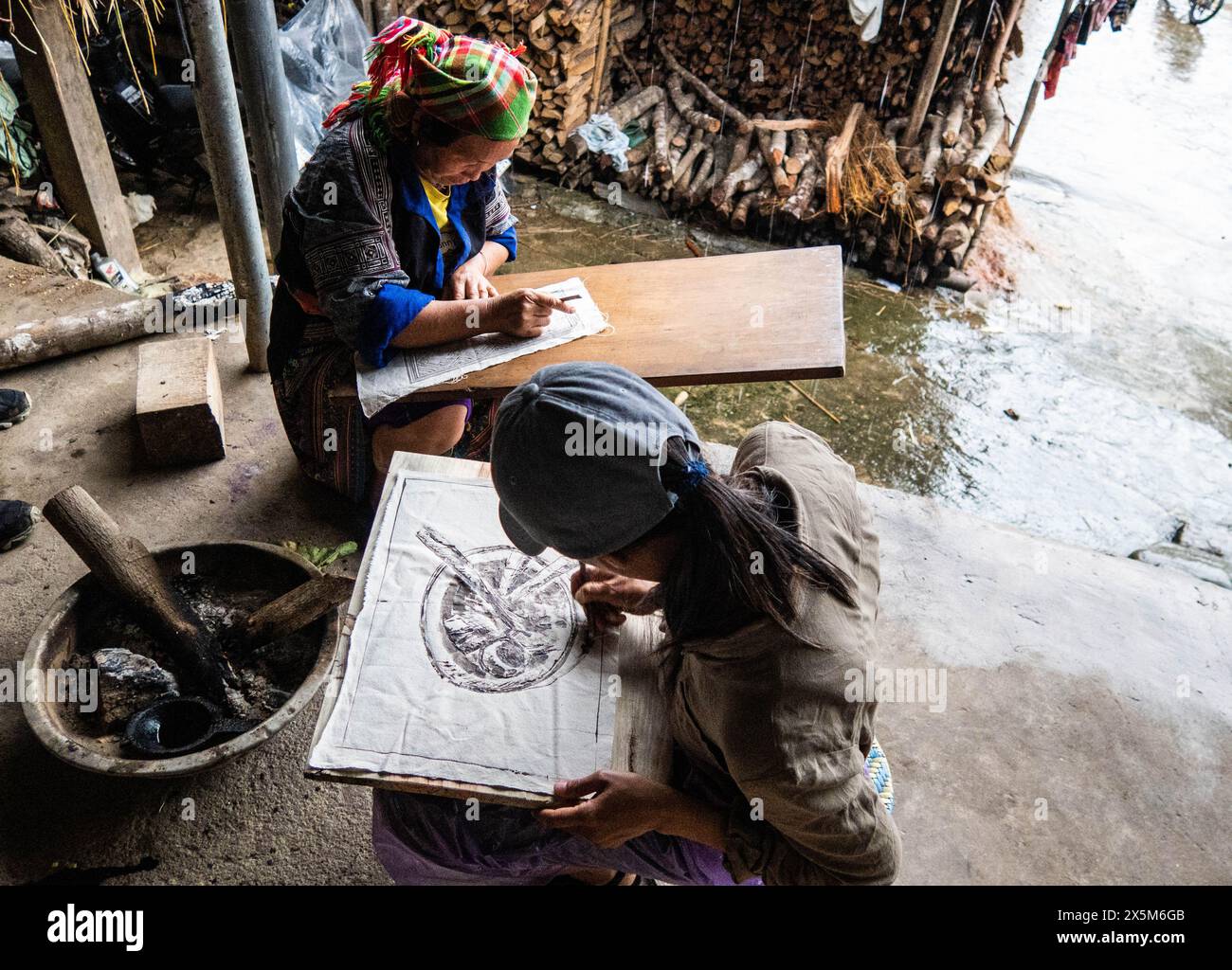 A Flower Hmong woman draws a pattern for her traditional embroidery, Mu ...