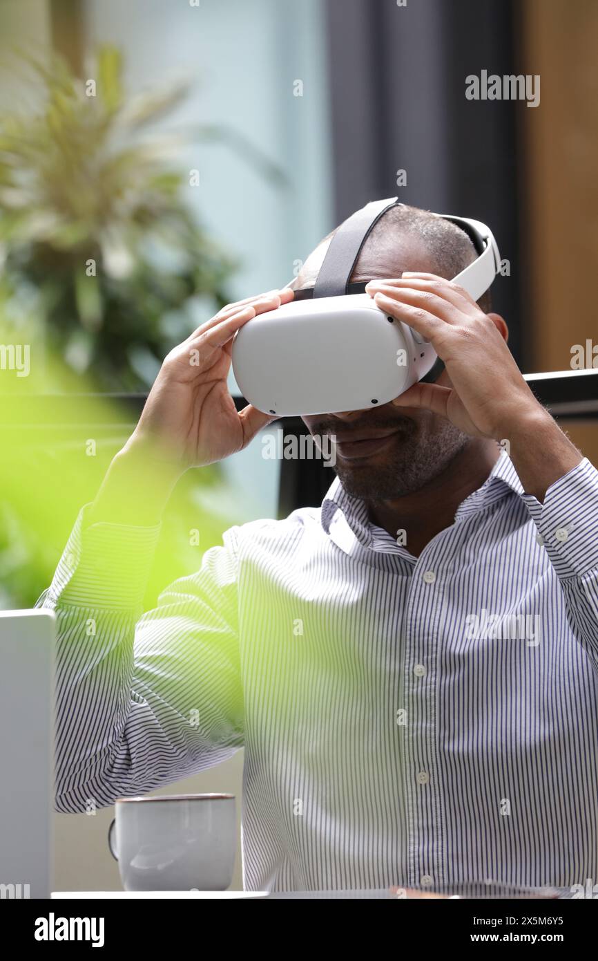 Businessman putting on virtual reality headset Stock Photo - Alamy