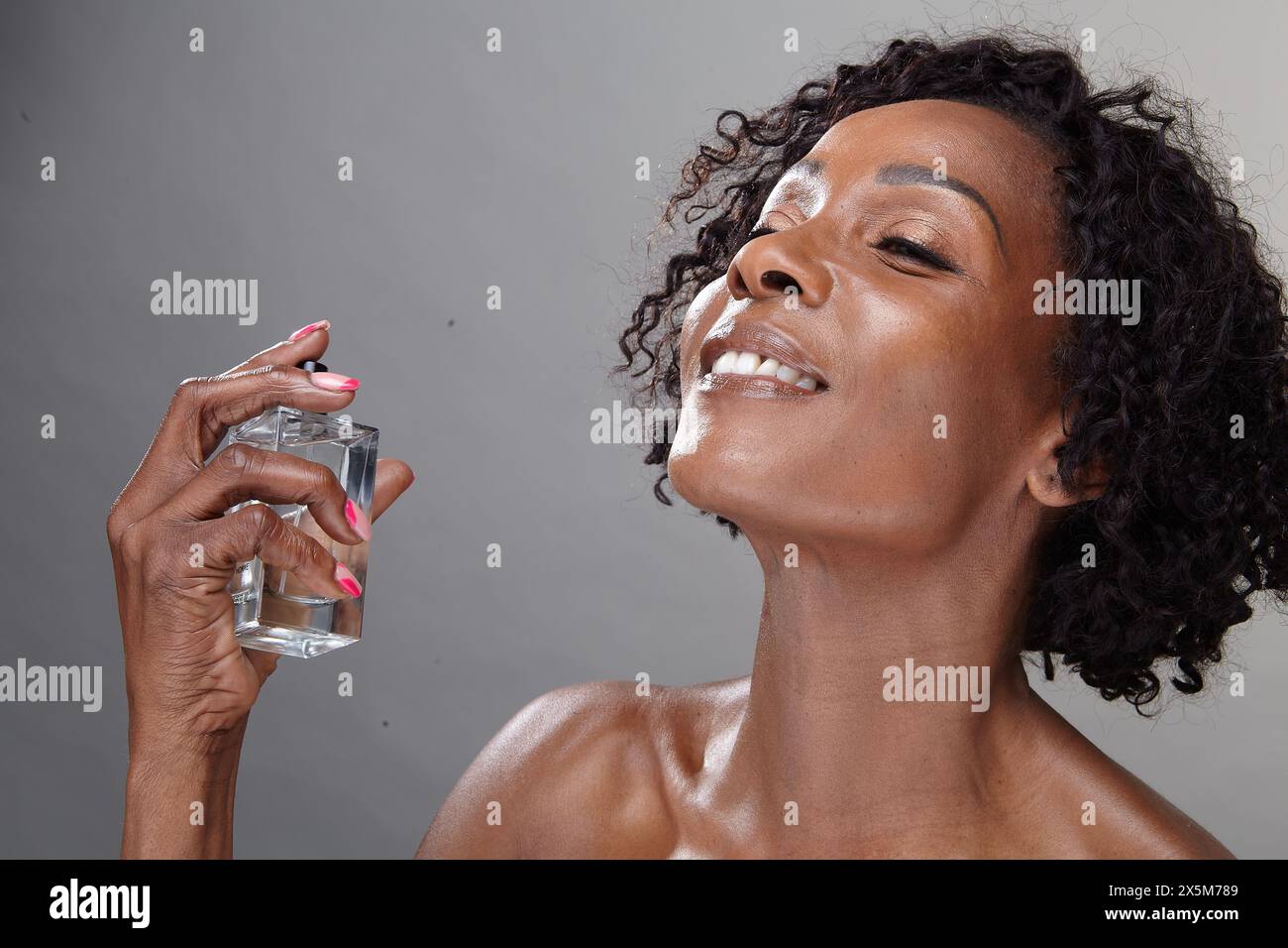 Studio shot of mature woman using perfume Stock Photo - Alamy
