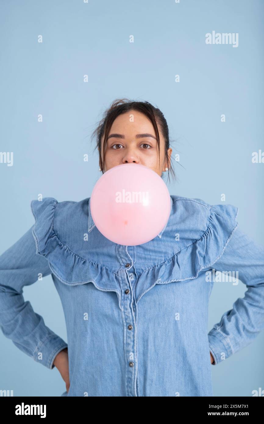 Studio portrait of young woman chewing gum and blowing bubble Stock ...