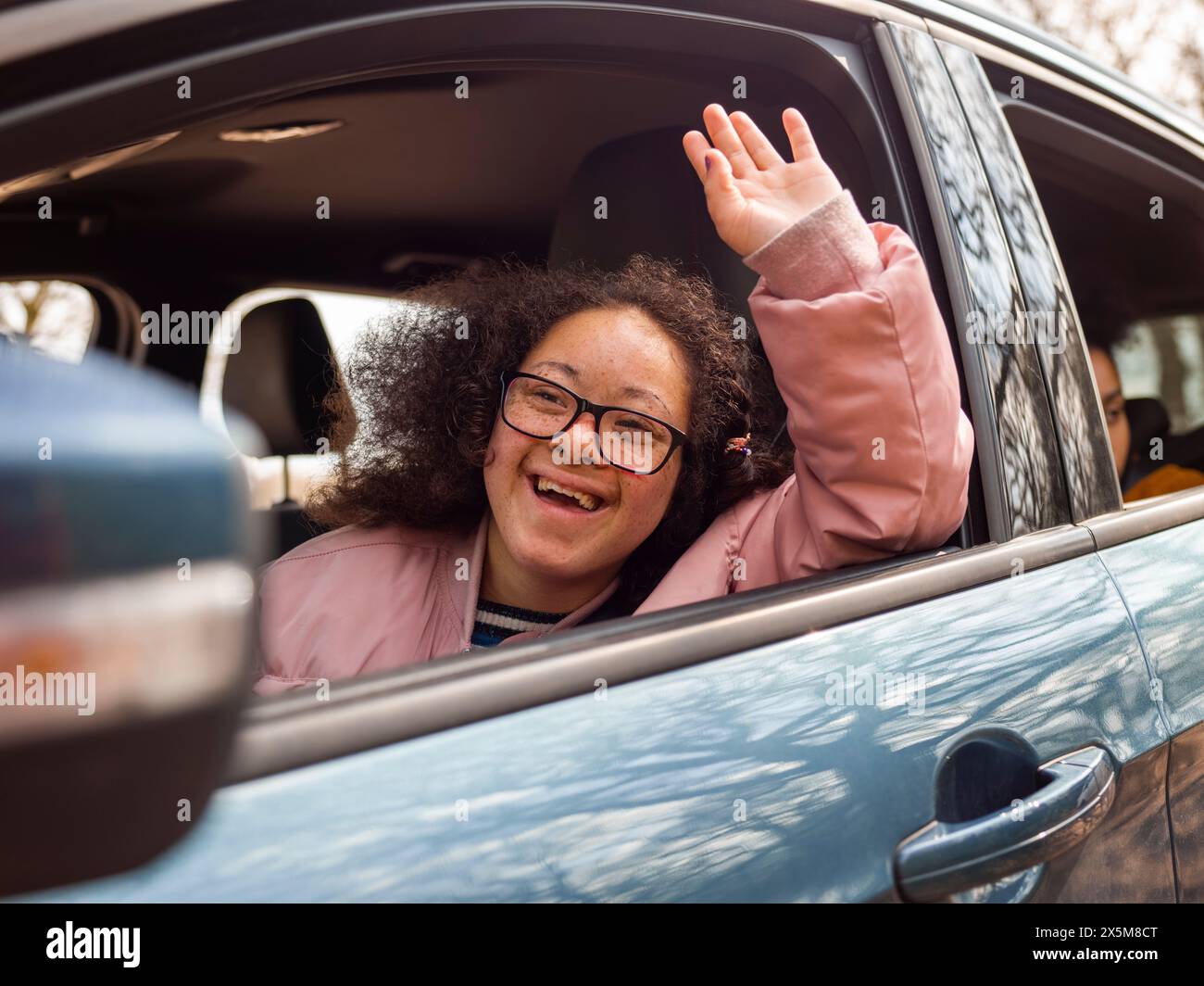 Girl waving out of car window Stock Photo - Alamy