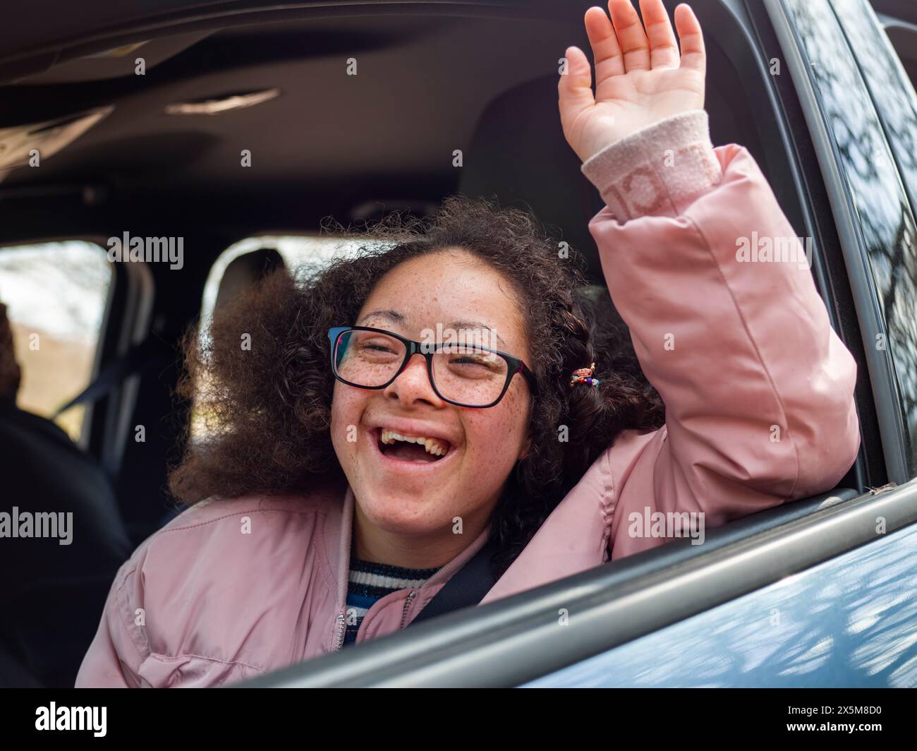 Girl waving out of car window Stock Photo - Alamy