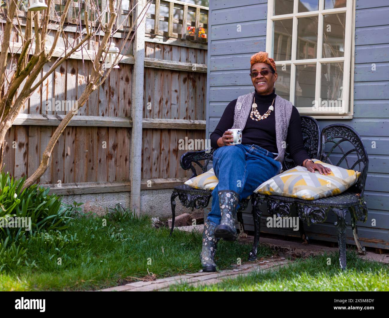 Woman relaxing on bench in backyard Stock Photo - Alamy
