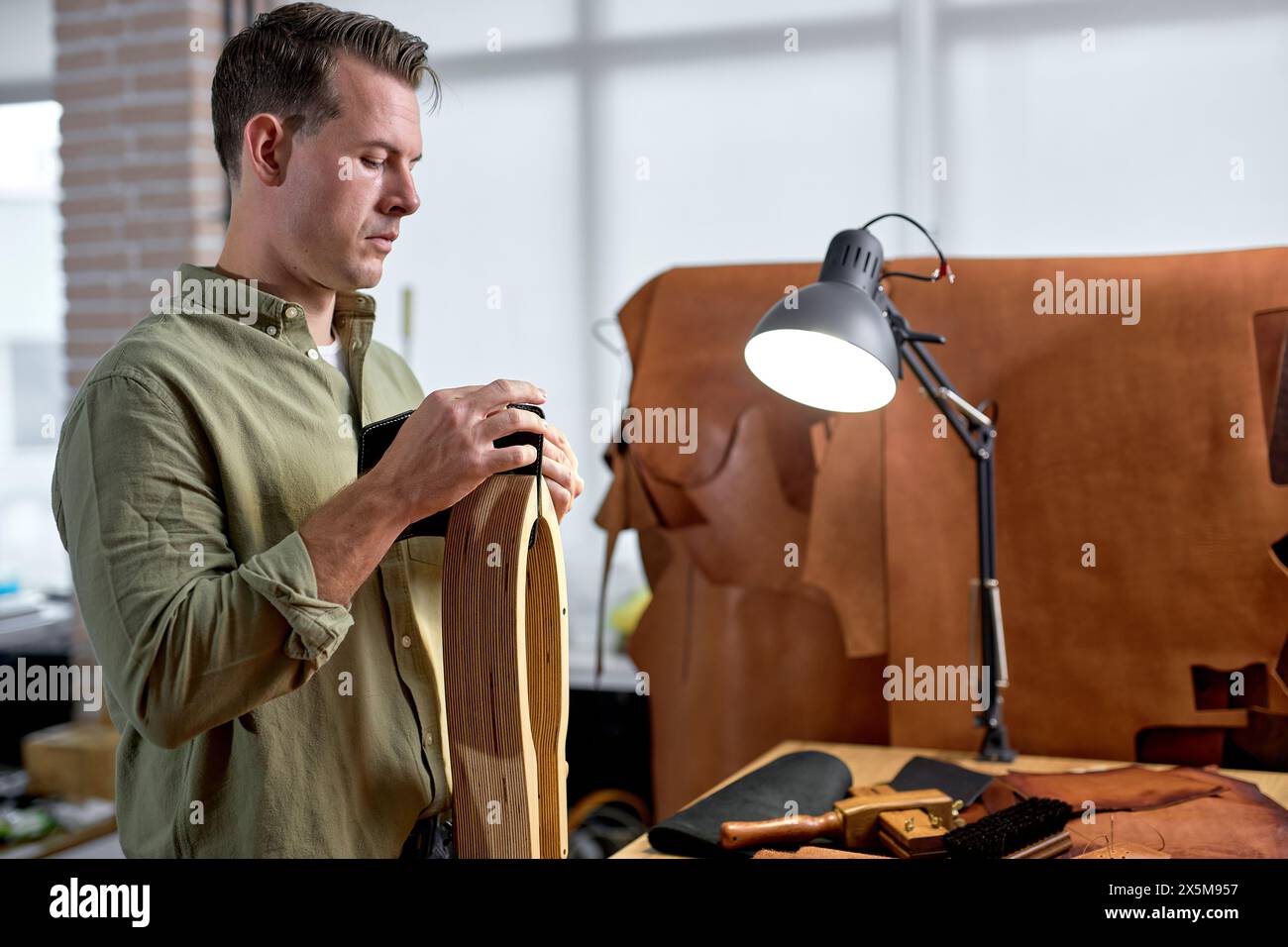 ambitious young craftsman working with leather stitching clamp. close ...
