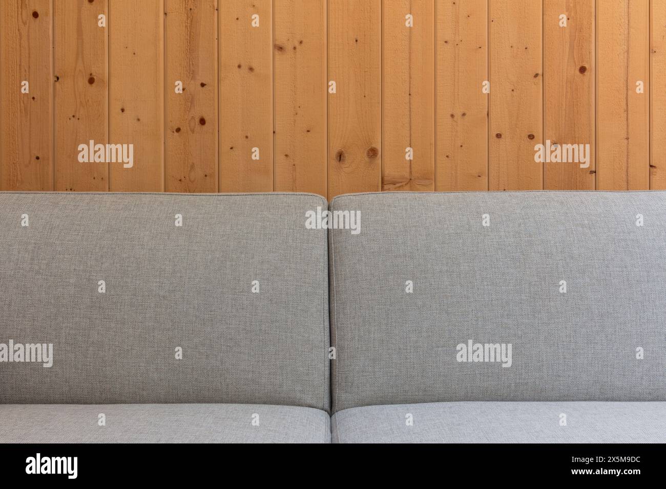 Detail of modern couch against a wood panel wall Stock Photo - Alamy