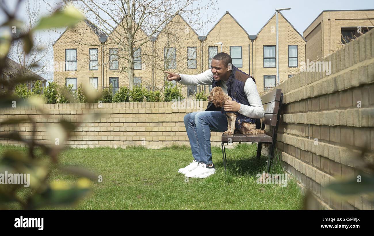 Man with dog sitting on park bench Stock Photo - Alamy