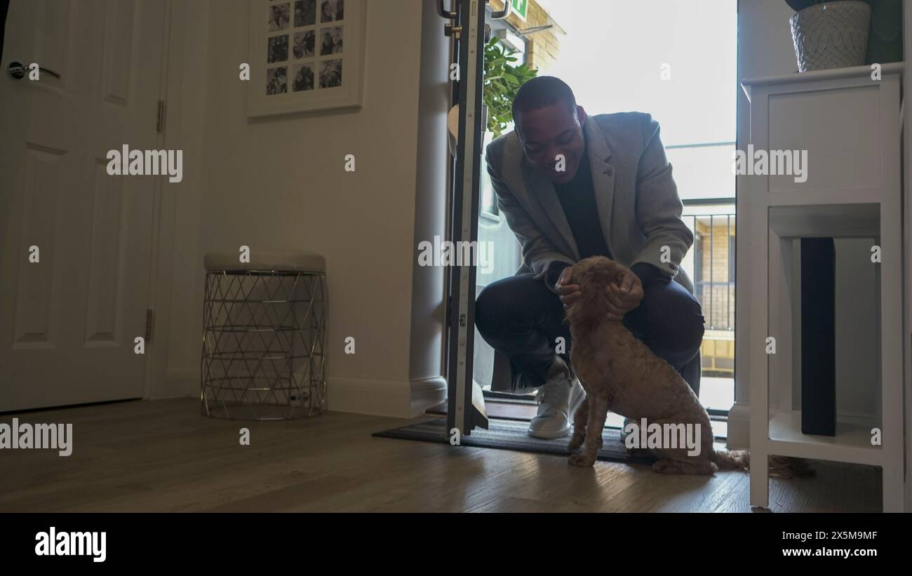 Dog greeting owner in doorway of house Stock Photo - Alamy