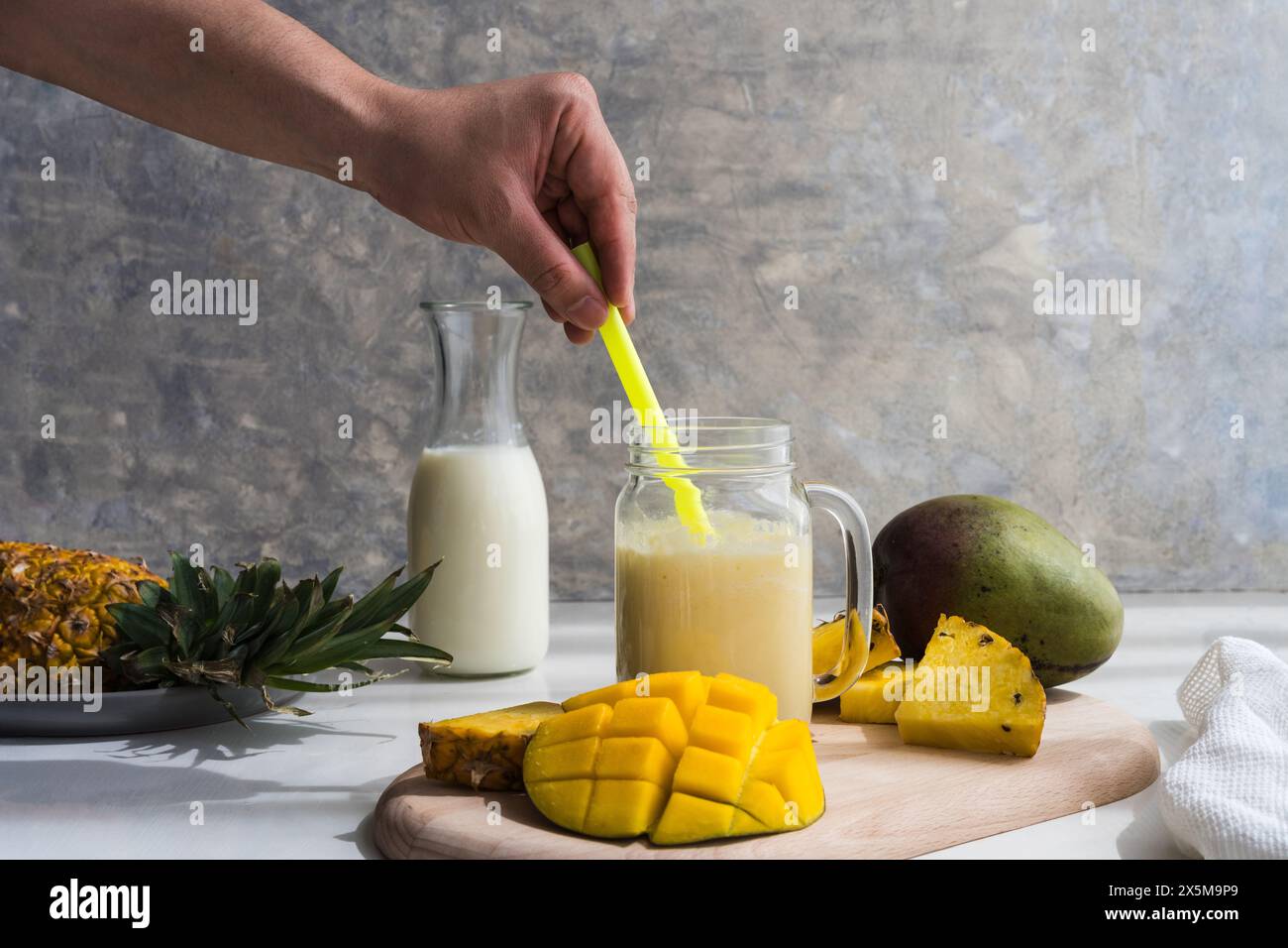 hand stirring an mango and pineapple smoothie with a straw Stock Photo ...