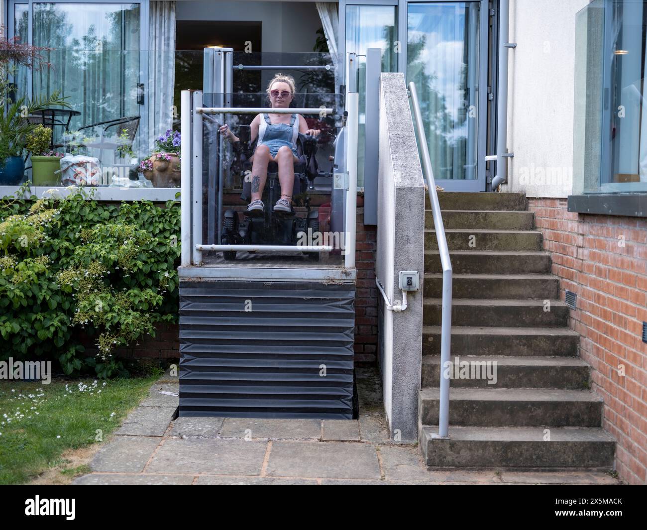 Woman in electric wheelchair using outdoor lift Stock Photo - Alamy