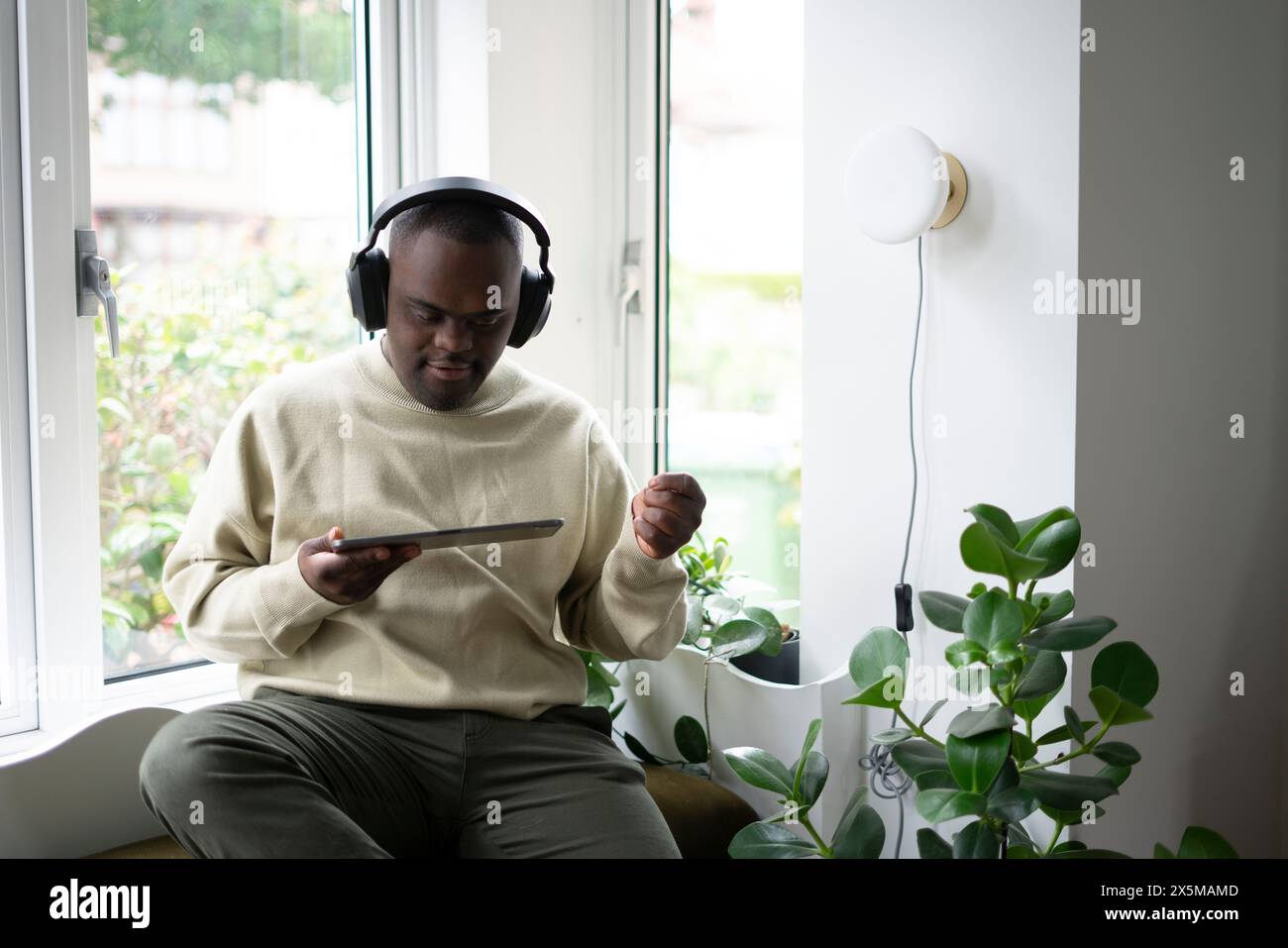 Man with Down syndrome using tablet and wearing headphones Stock Photo ...