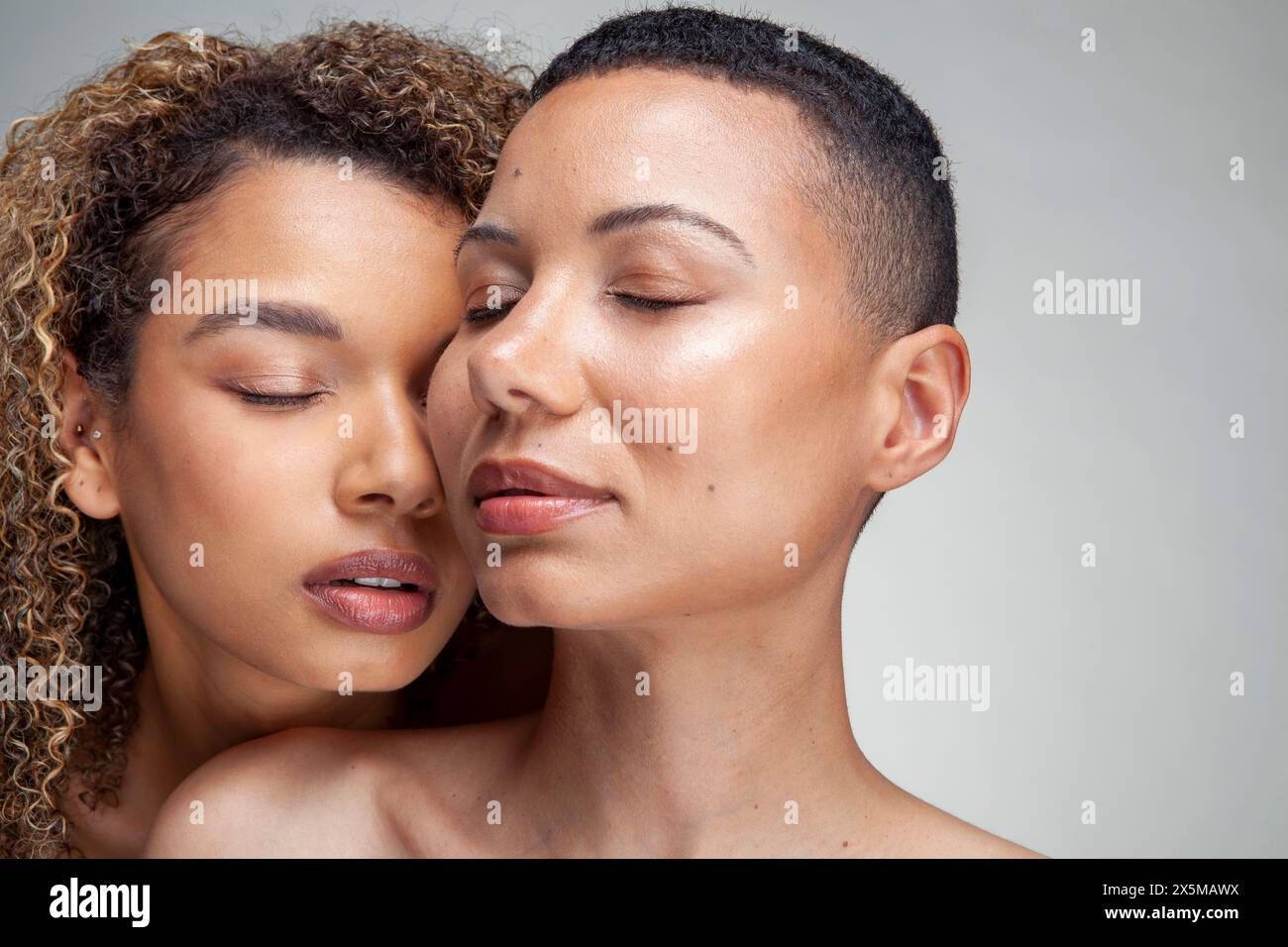 Studio portrait of two women cheek to cheek Stock Photo - Alamy
