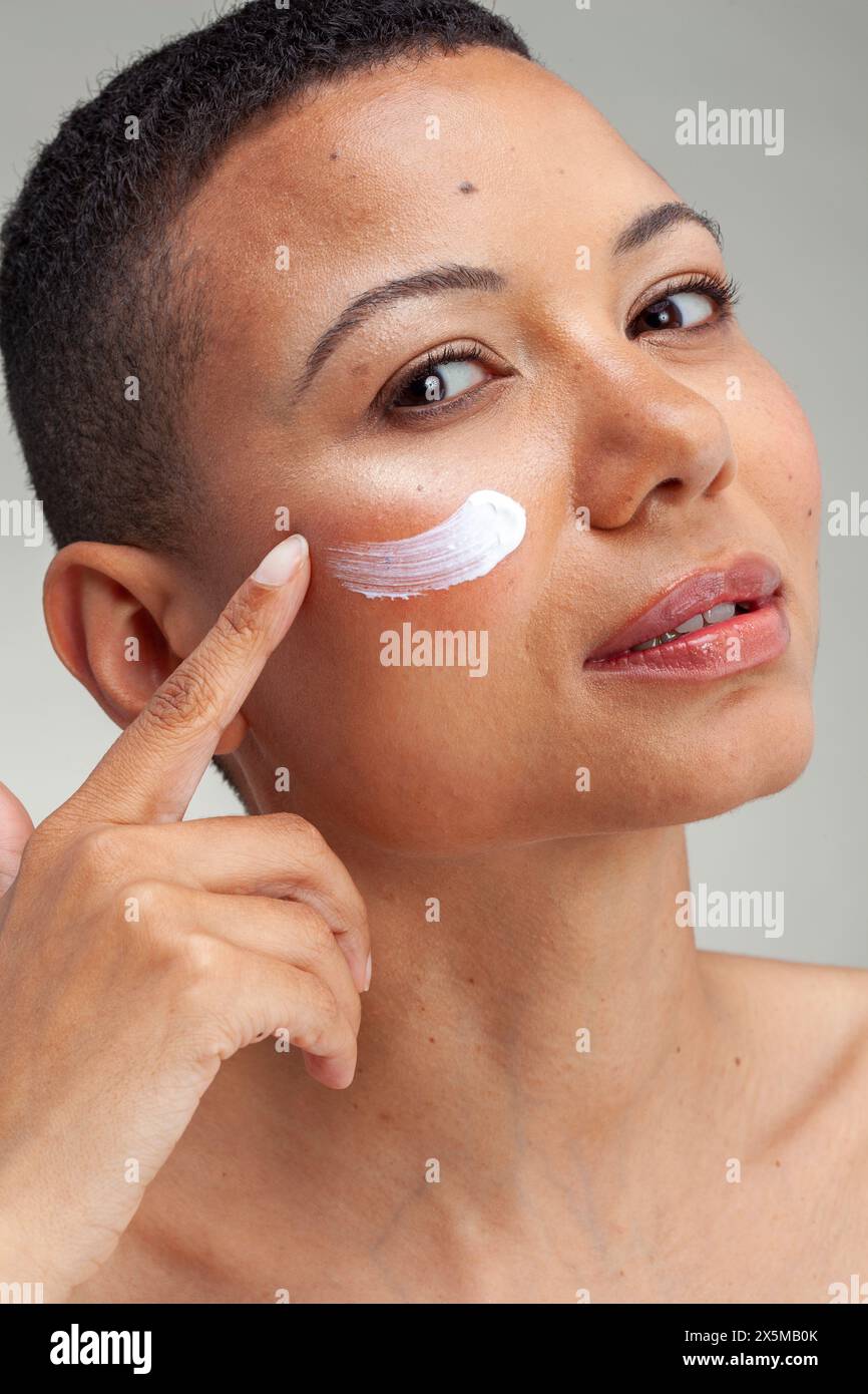 Studio portrait of woman applying facial cream Stock Photo - Alamy