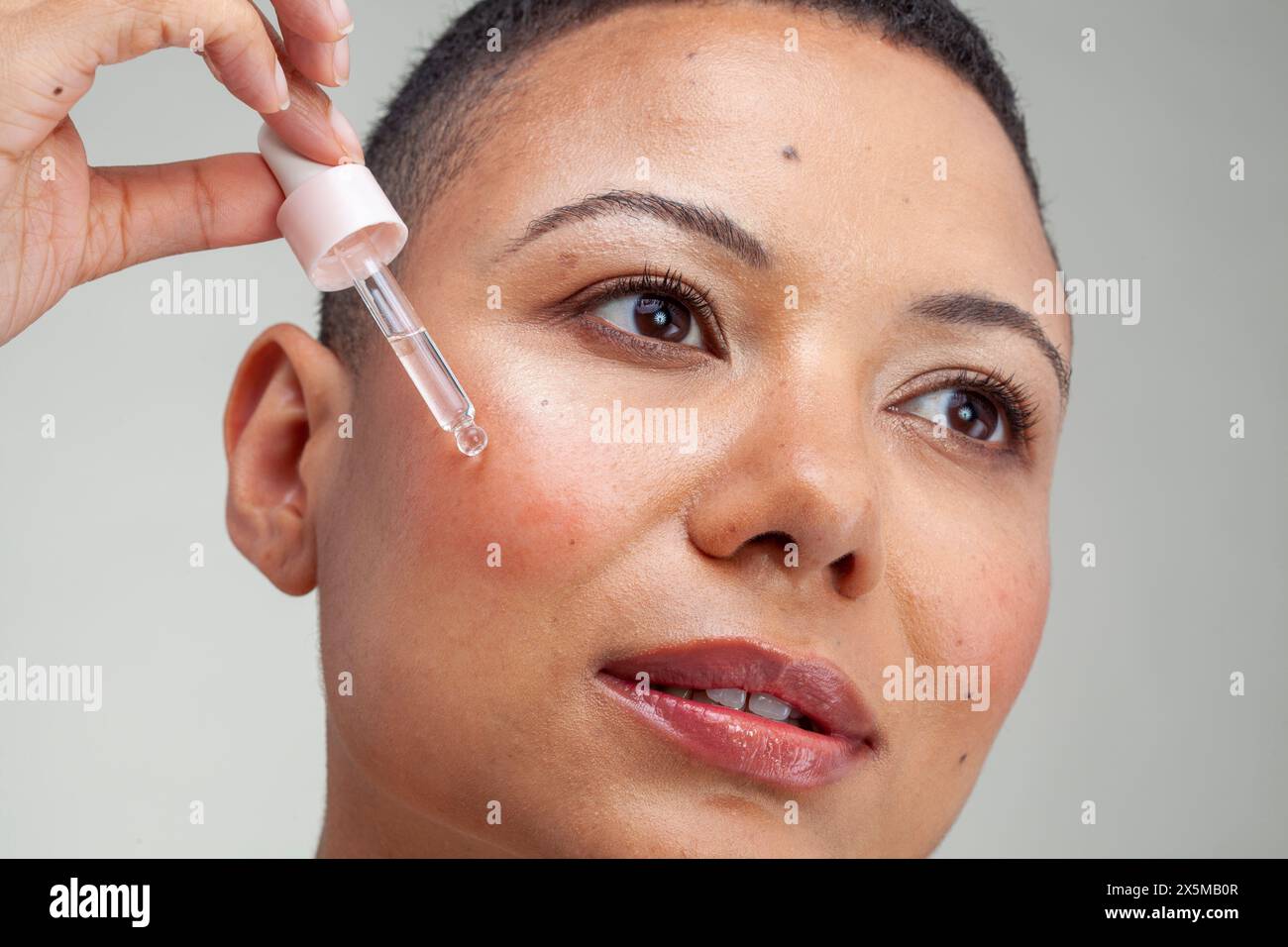 Close-up of woman applying serum on cheek Stock Photo - Alamy