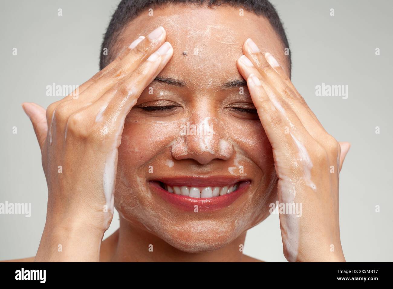 Close-up of smiling woman washing face Stock Photo - Alamy