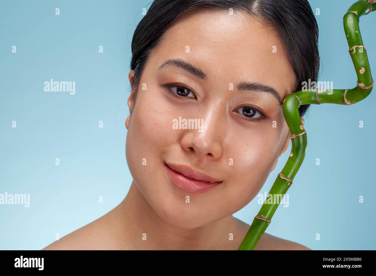 Studio portrait of woman with green bamboo twig Stock Photo - Alamy