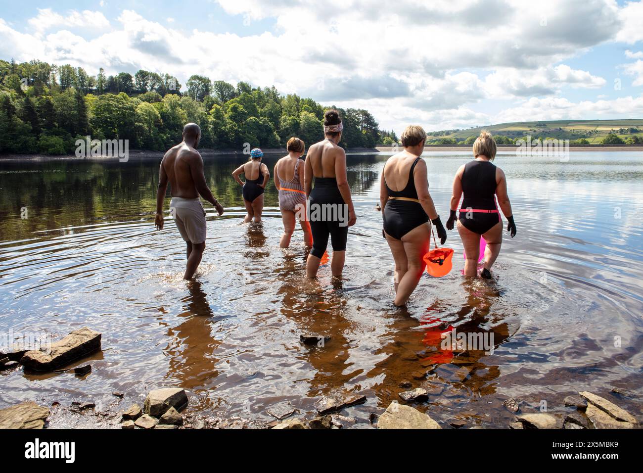 Rear view of group of friends entering lake, Yorkshire, UK Stock Photo ...