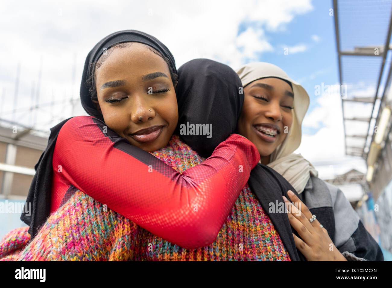 Young women wearing hijabs hugging in city Stock Photo - Alamy
