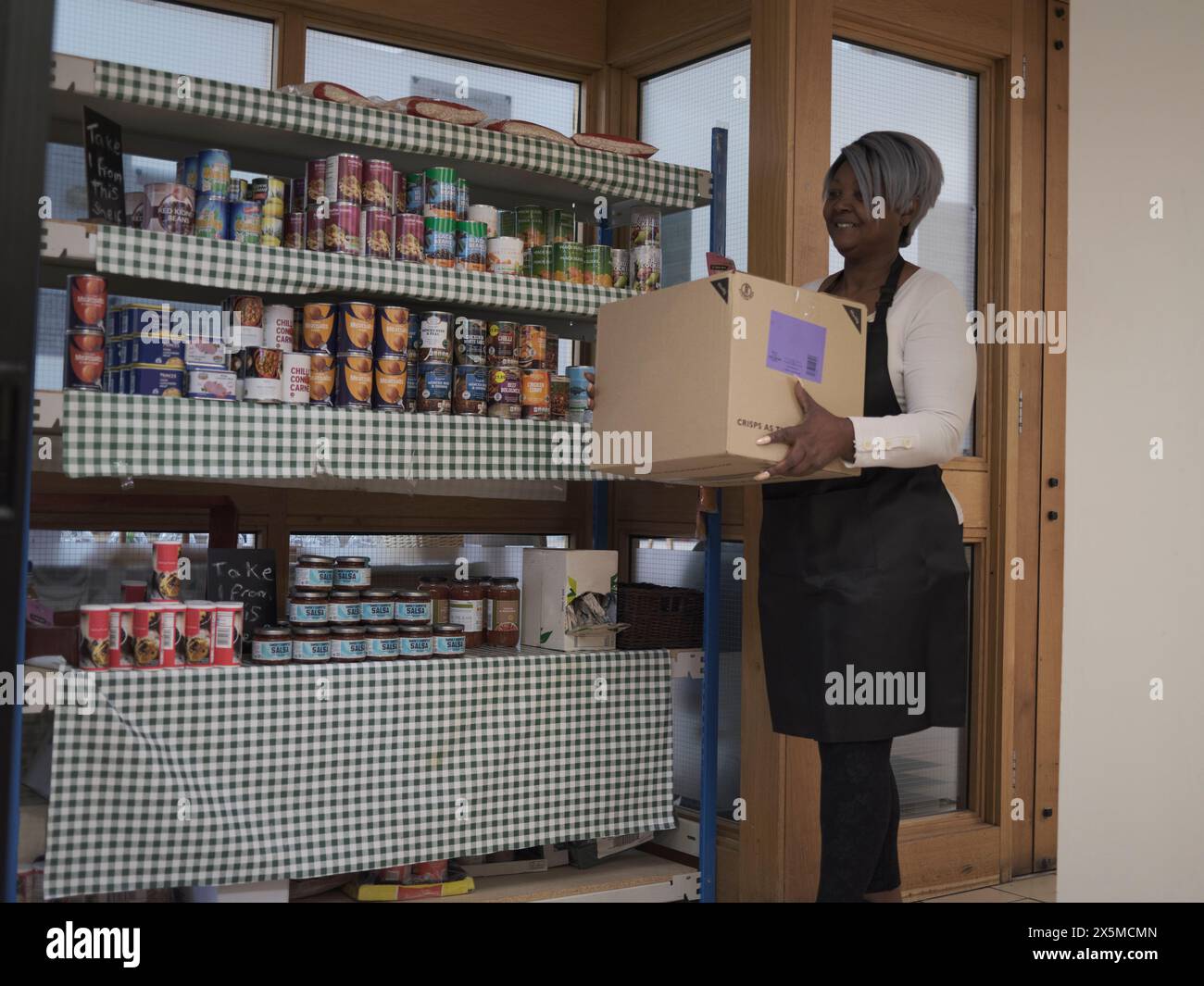 Female volunteer working in community food center Stock Photo - Alamy