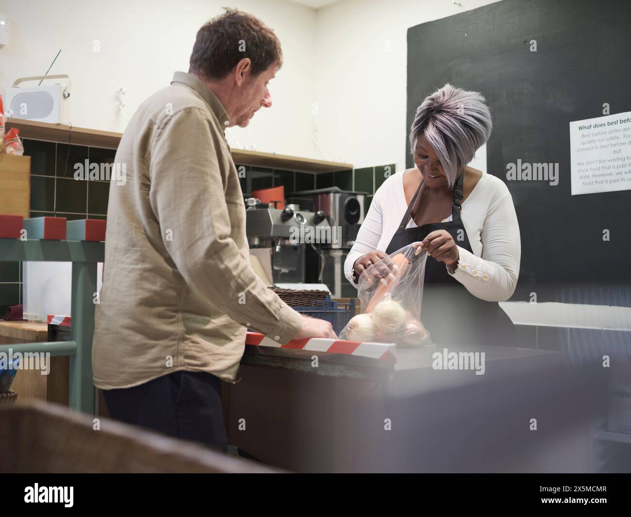 Volunteer giving man vegetables in community food center Stock Photo ...
