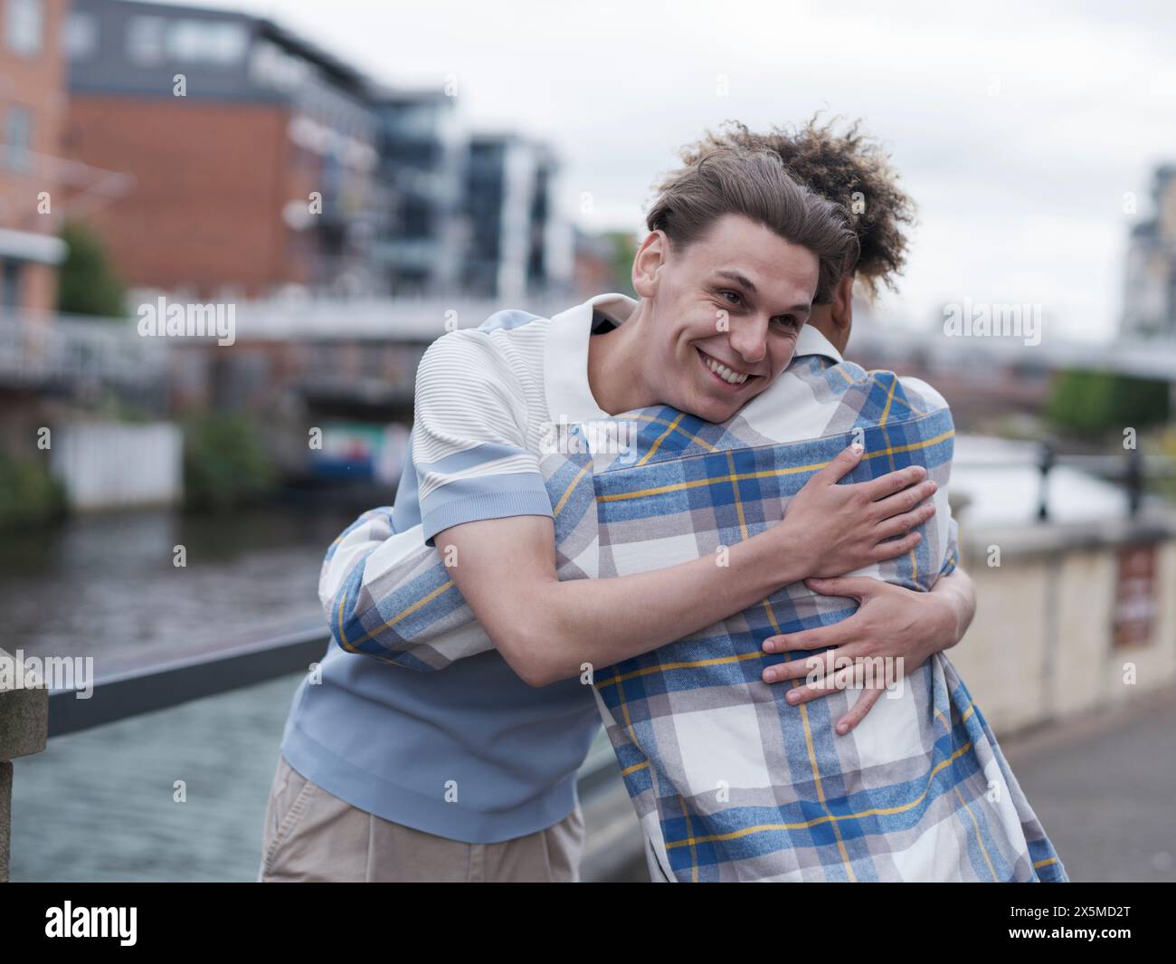 Young men hugging Stock Photo - Alamy