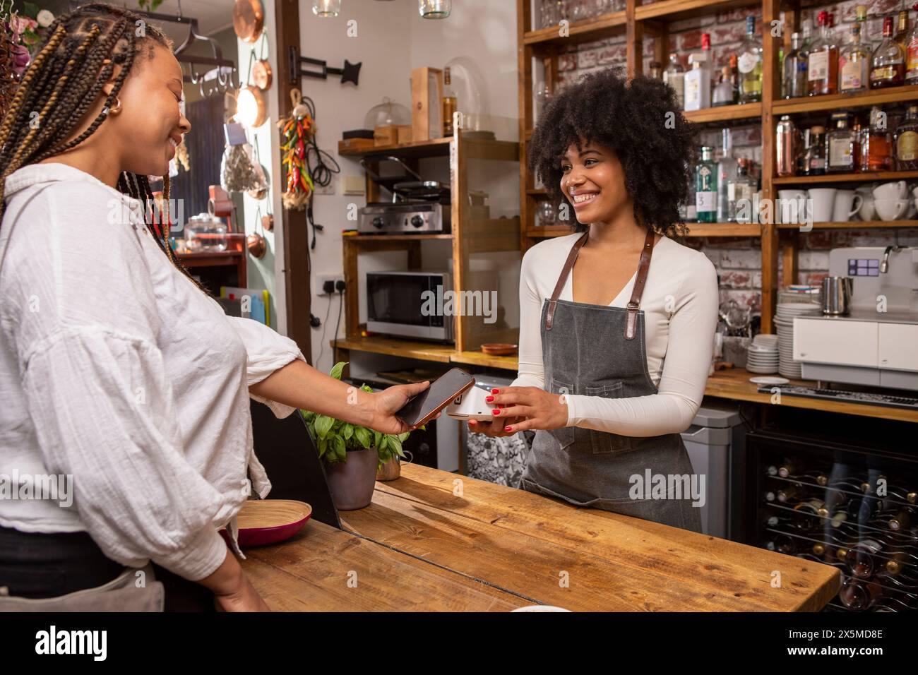 UK, London, Smiling customer paying with credit card at cafe Stock ...