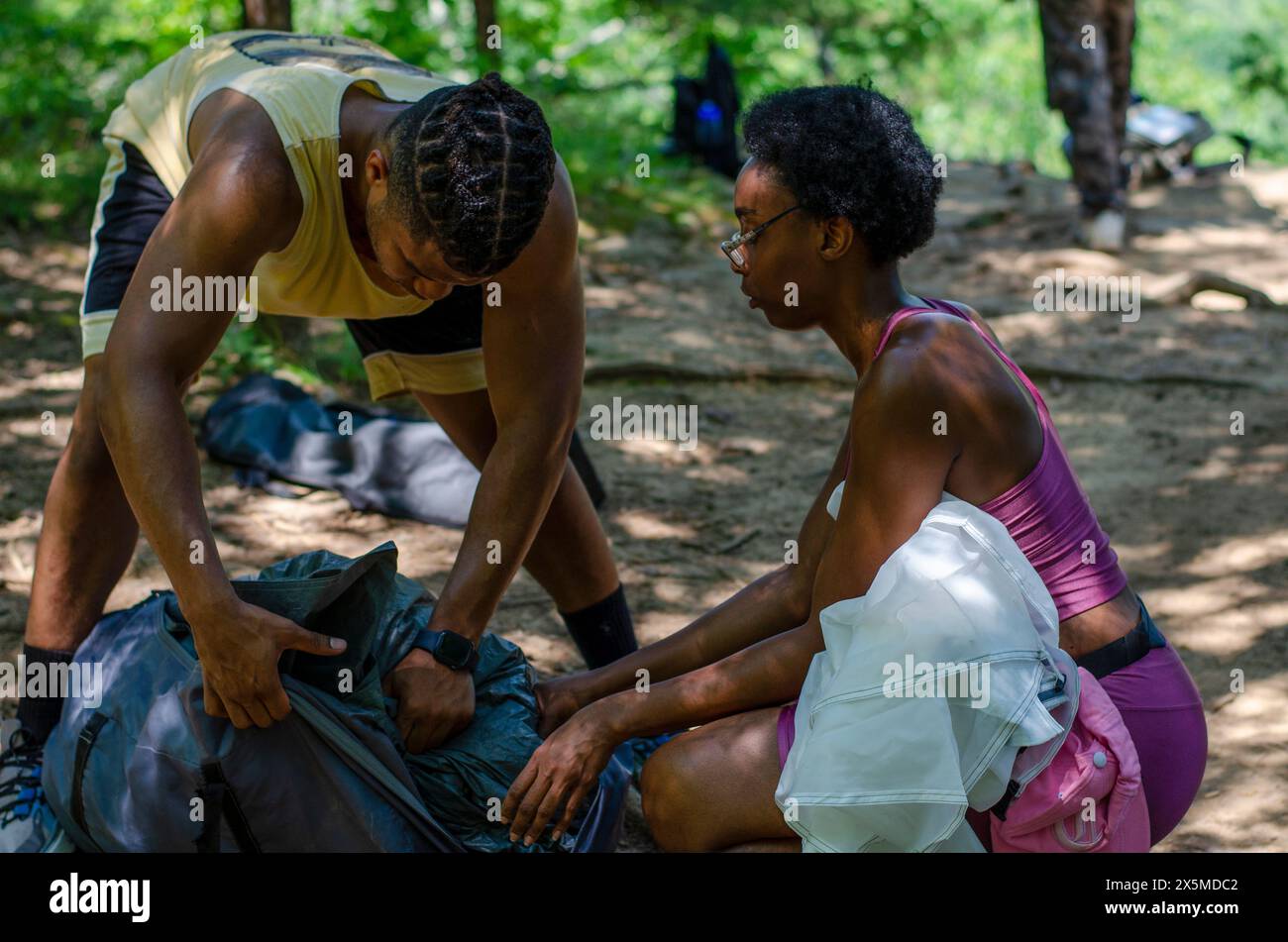 Young people setting up camp in forest Stock Photo - Alamy