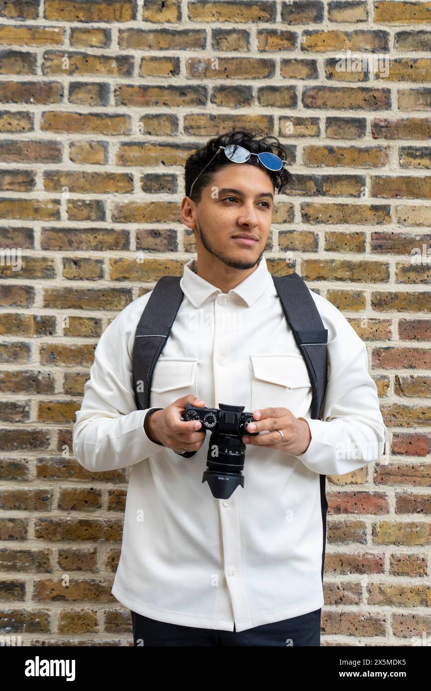 Portrait of young man holding camera Stock Photo - Alamy