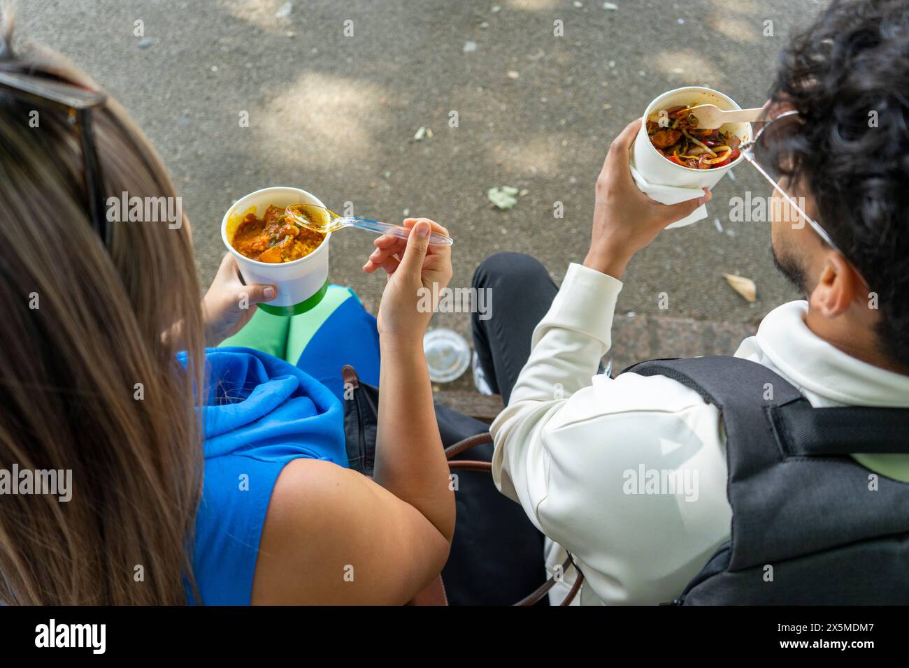 Rear view of tourist couple eating street food Stock Photo - Alamy