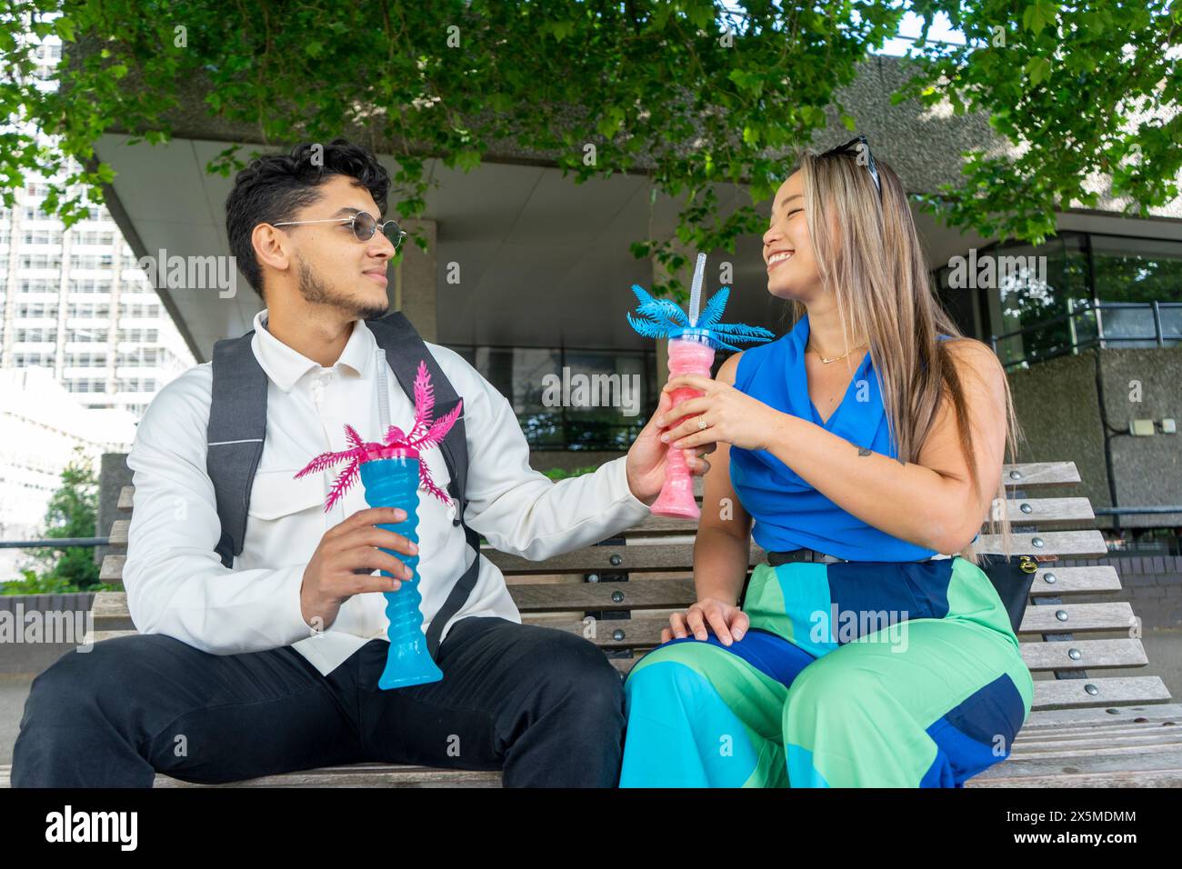 Tourist couple sitting on park bench drinking cocktails Stock Photo - Alamy