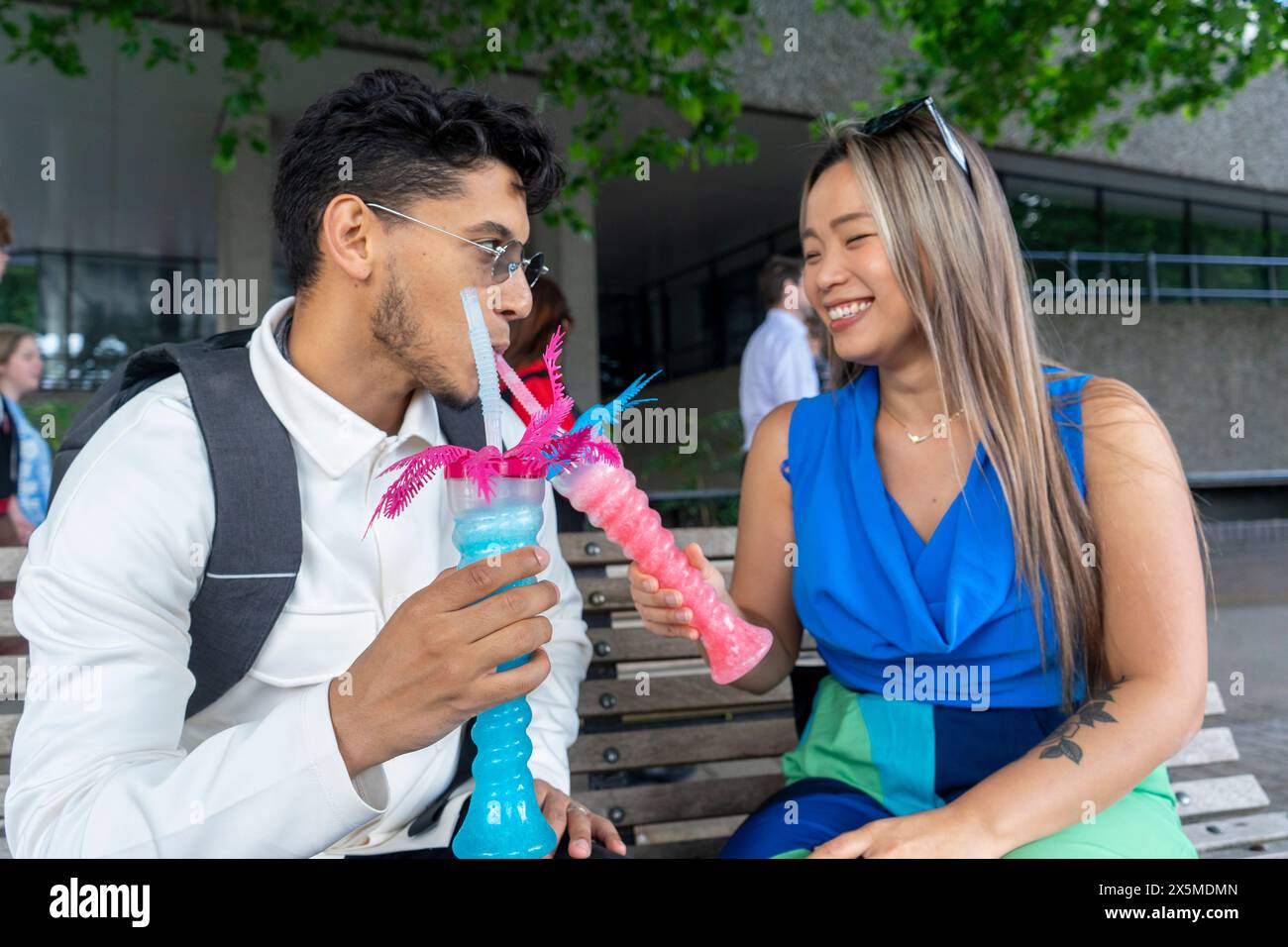 Tourist couple sitting on park bench drinking cocktails Stock Photo - Alamy