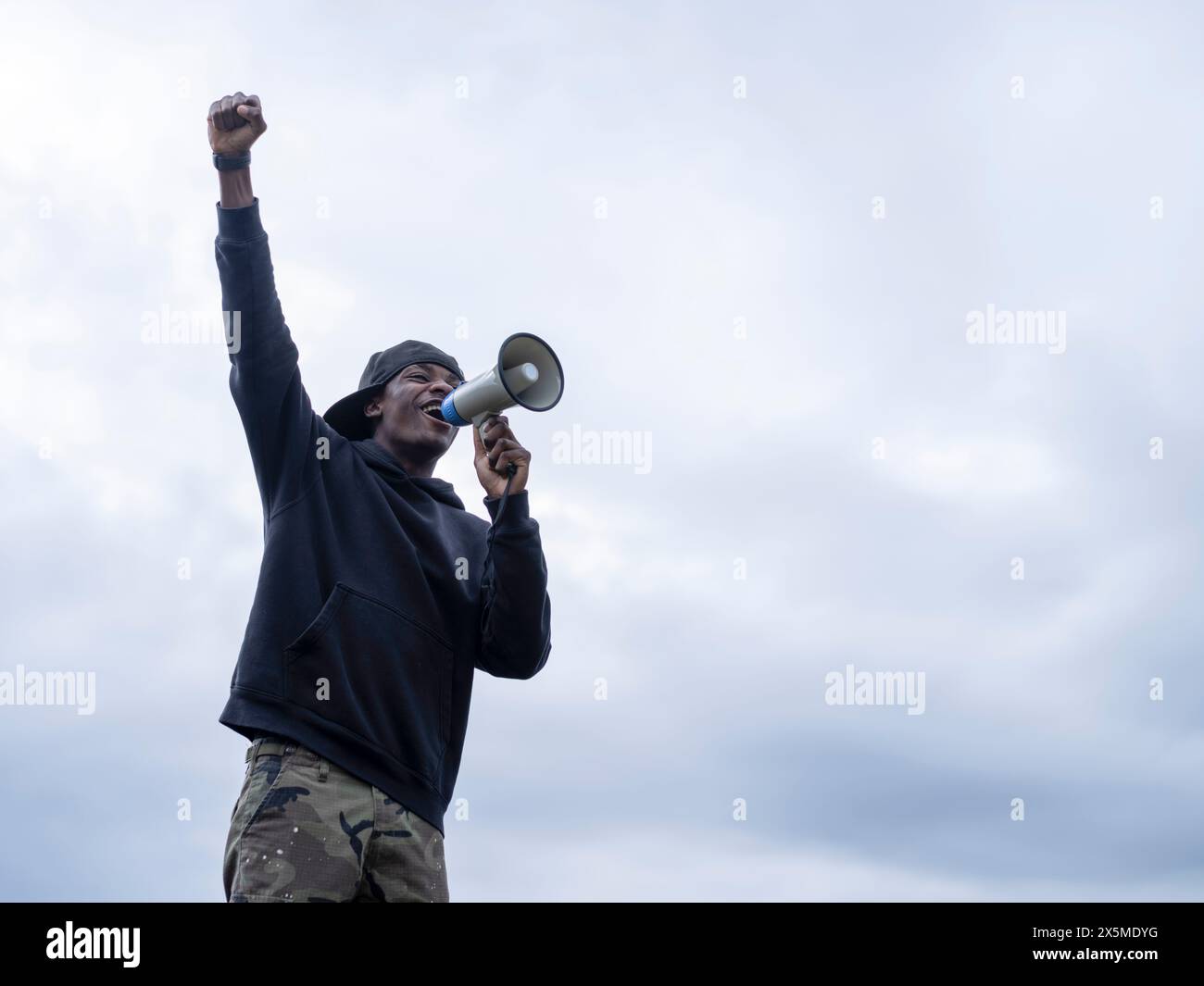 Young man using bullhorn under stormy sky Stock Photo - Alamy