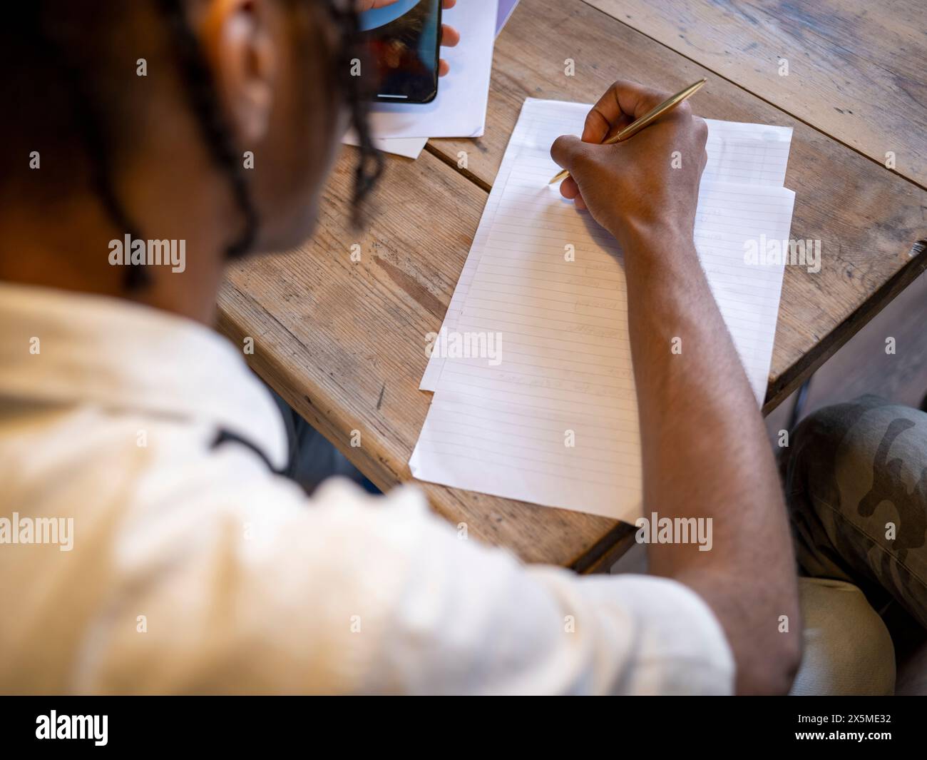 Teenage (16-17) boy writing, over the shoulder view Stock Photo - Alamy