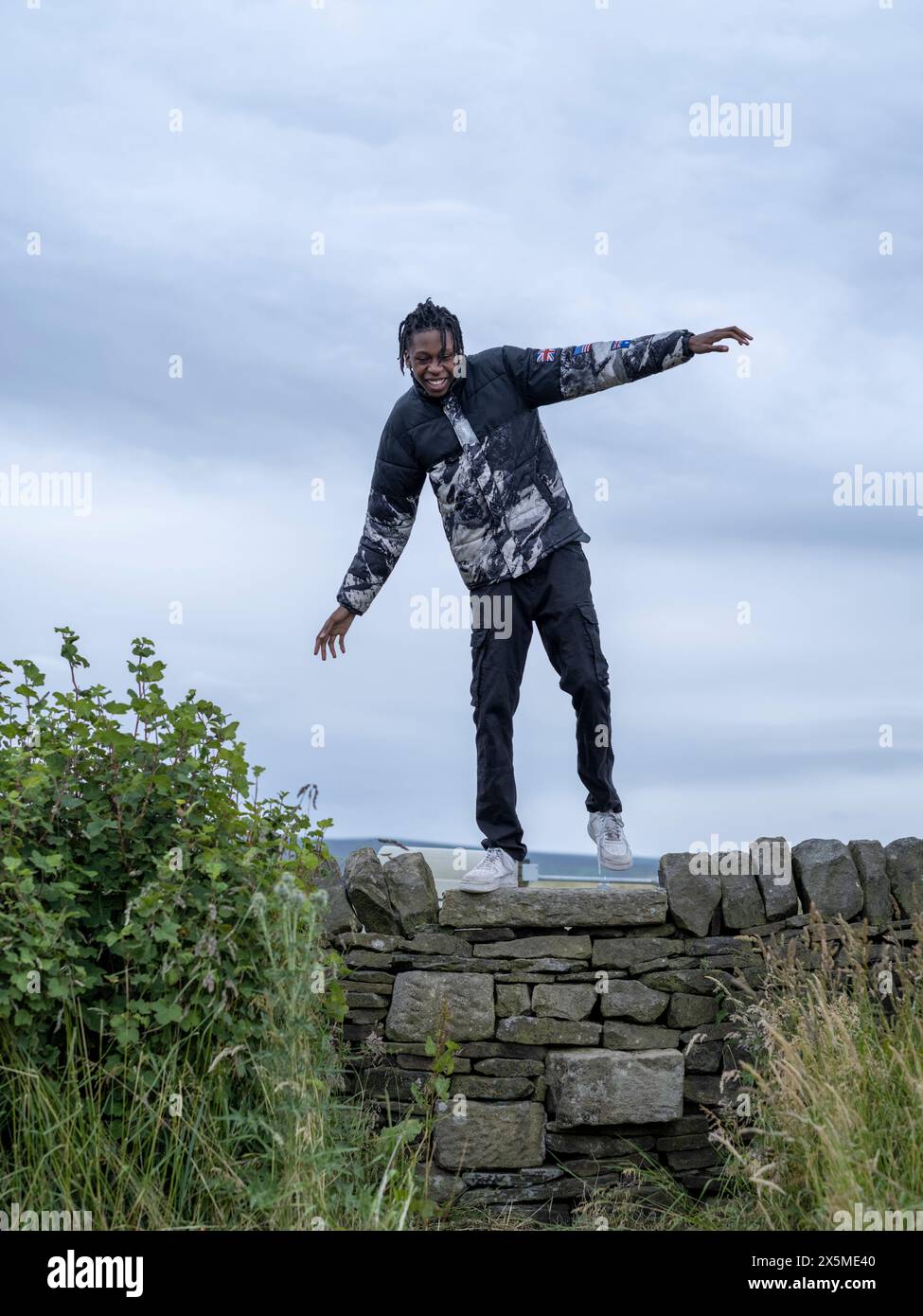 Young man balancing on stone wall Stock Photo - Alamy