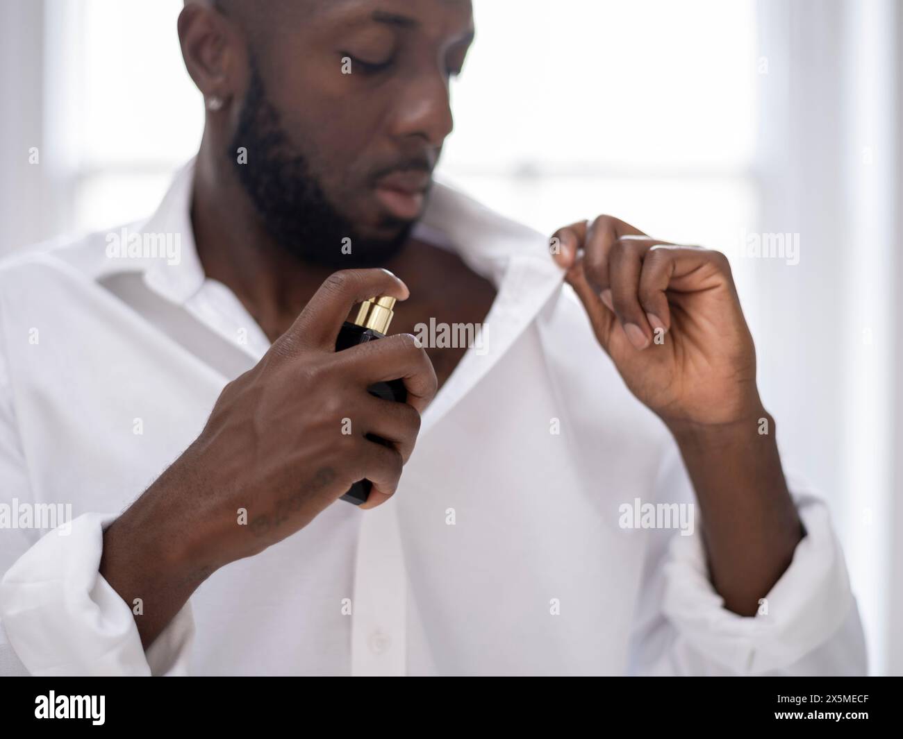 Person spraying perfume on white shirt collar Stock Photo - Alamy