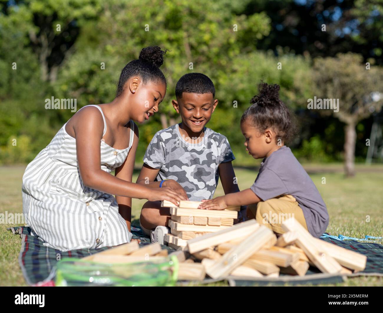 Siblings (2-3, 8-9, 10-11) playing block removal game Stock Photo - Alamy