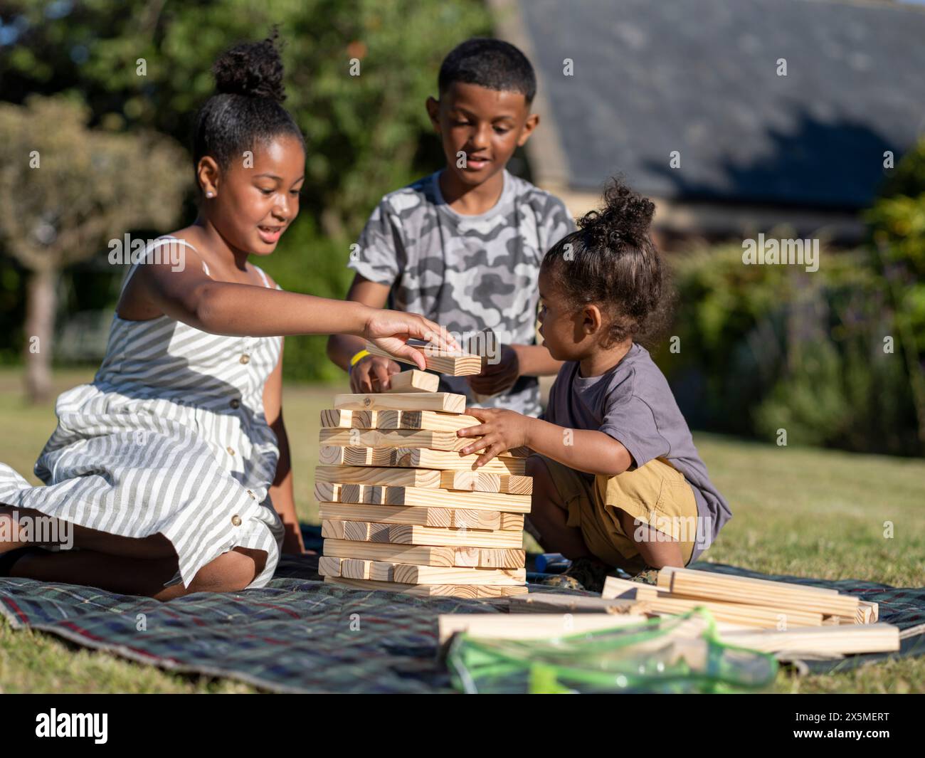 Siblings (2-3, 8-9, 10-11) playing block removal game Stock Photo - Alamy