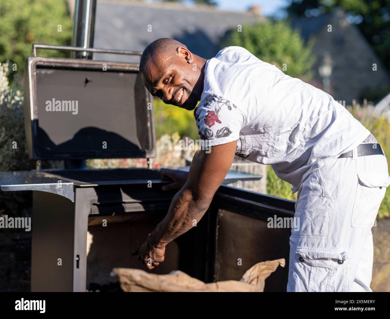 Man starting barbecue grill Stock Photo - Alamy