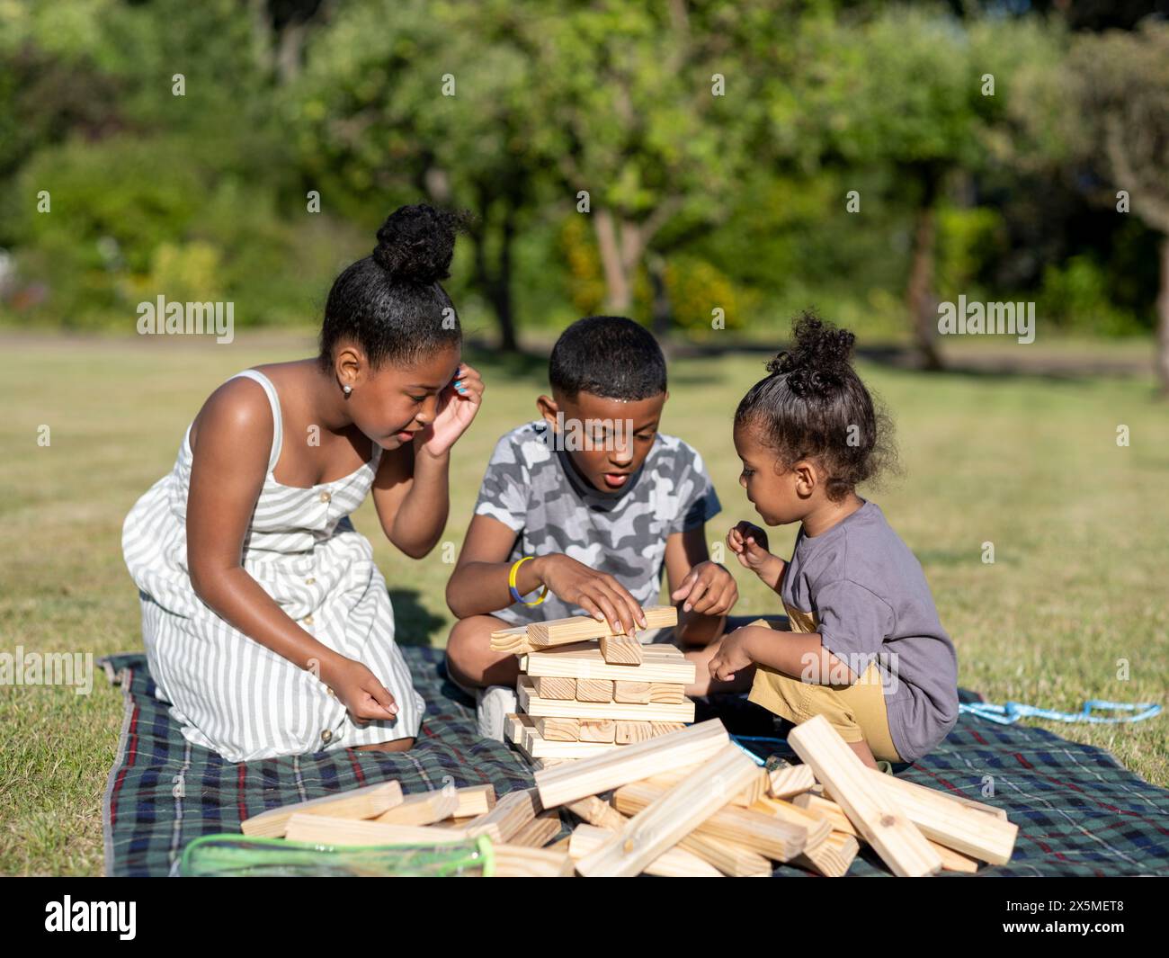 Siblings (2-3, 8-9, 10-11) playing block removal game Stock Photo - Alamy