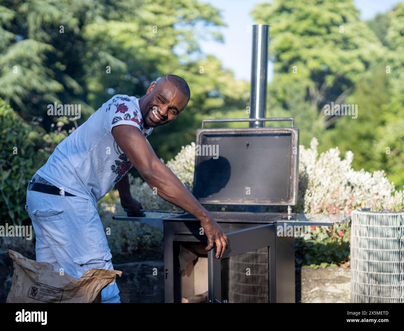 Man starting barbecue grill Stock Photo - Alamy