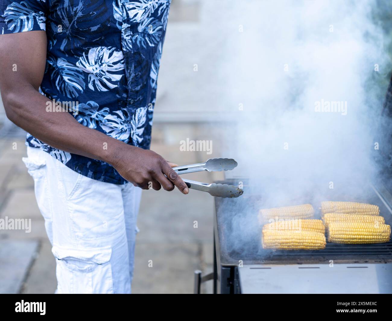 Man grilling corn on barbecue grill Stock Photo - Alamy