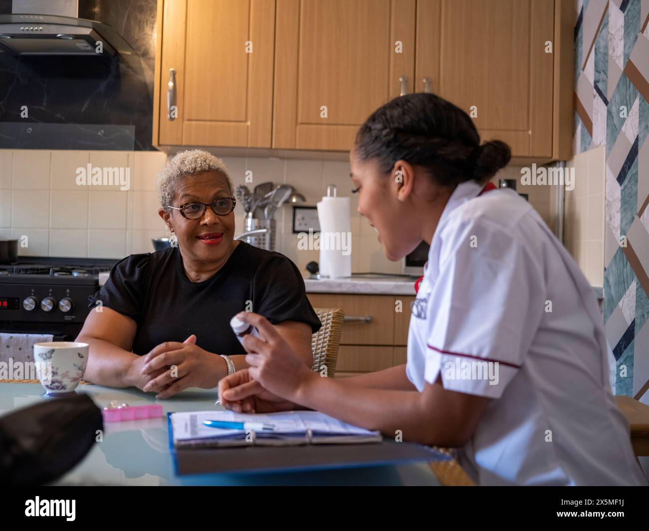 Nurse visiting mature woman at her house, showing medications Stock ...